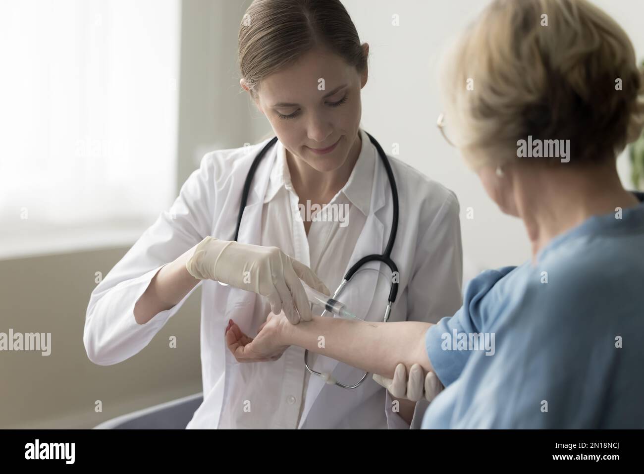Focused medical nurse giving shot to vein of older patient Stock Photo ...