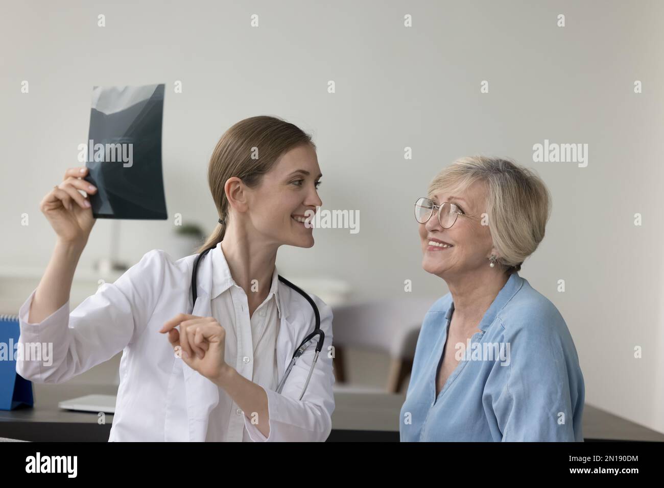 Happy doctor woman showing Xray scan to elder patient Stock Photo - Alamy