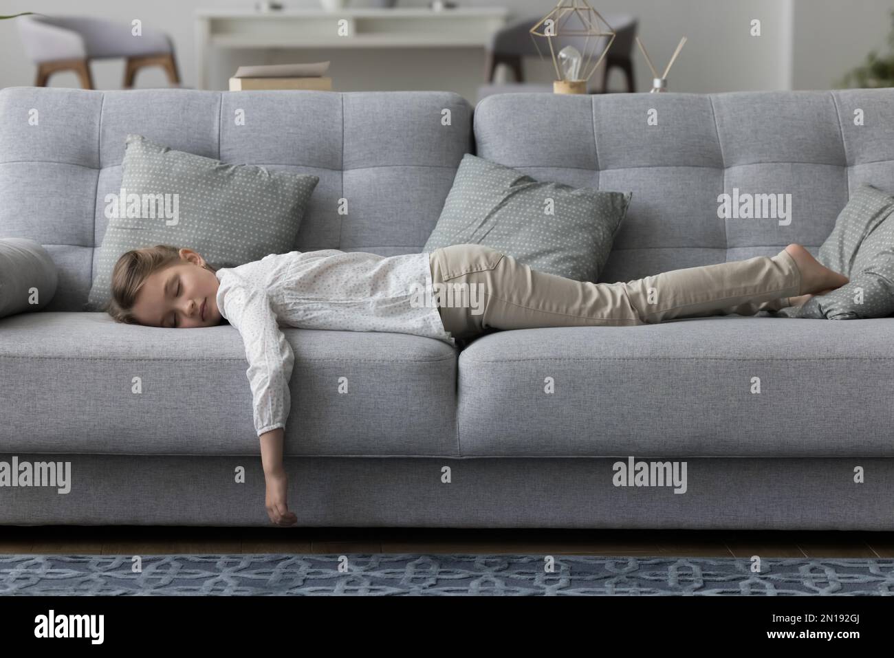 Calm sleepy little kid girl lying on belly on couch Stock Photo - Alamy