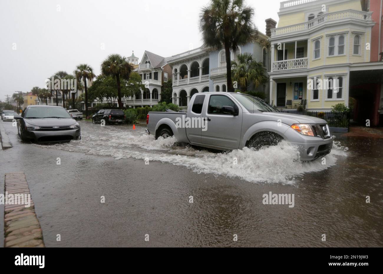 A car drives through a flooded street in Charleston, S.C., Saturday ...