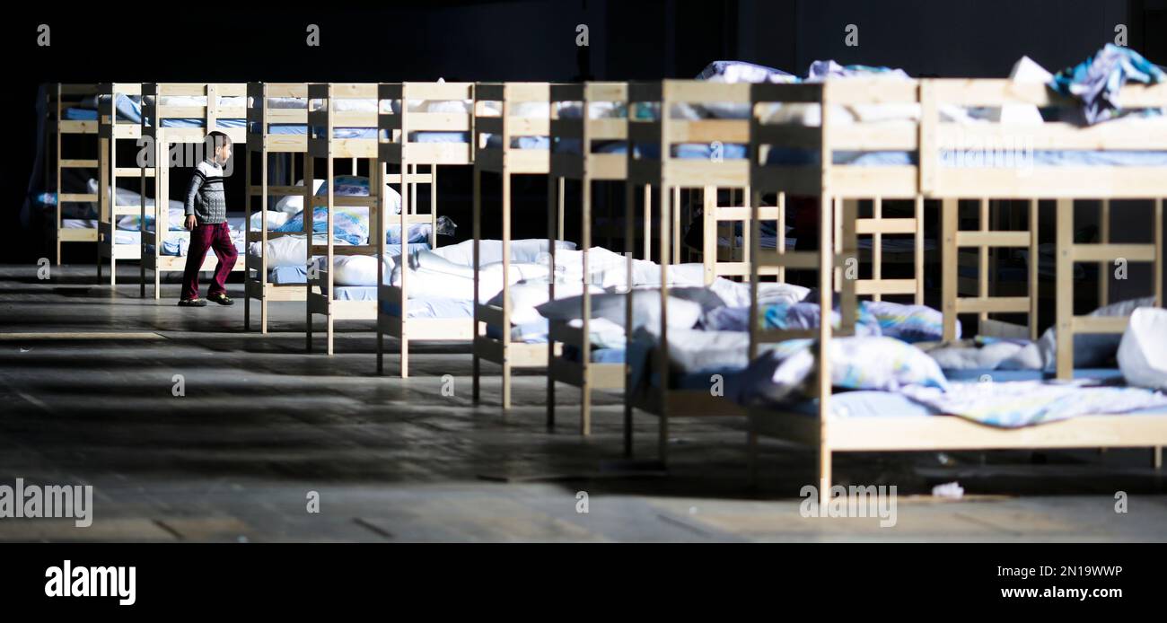 A boy walks between a line of bunk beds in a new temporary shelter for ...