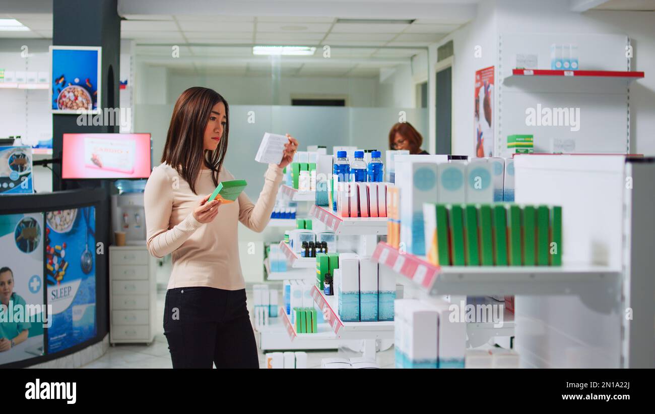 Young person examining boxes of medicaments on shelves in pharmacy ...
