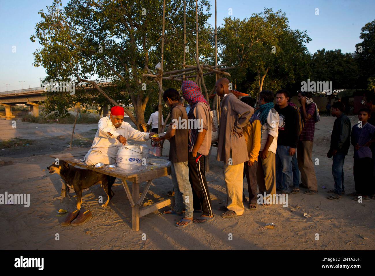 Poor men wait in a queue to receive food handed out as an act of ...