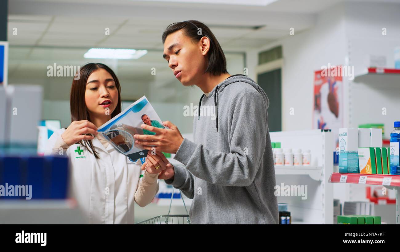 Specialist helping male client with drugstore leaflet, giving medical ...