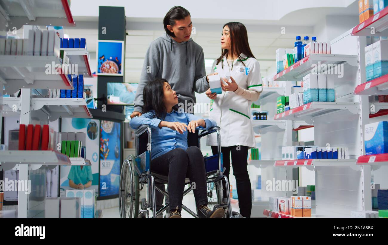 Pharmaceutical worker giving pills box to customer in wheelchair, male ...