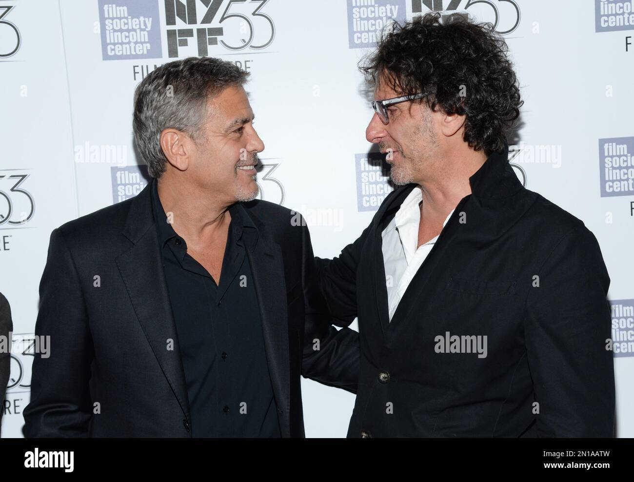 Actor George Clooney, left, shares a laugh with director Joel Coen on the red carpet before a ...