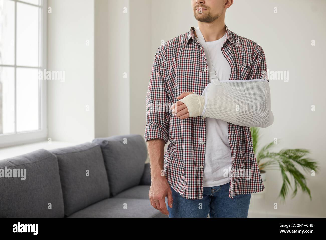 Young Caucasian man with broken wrist wears arm sling bandage on his ...