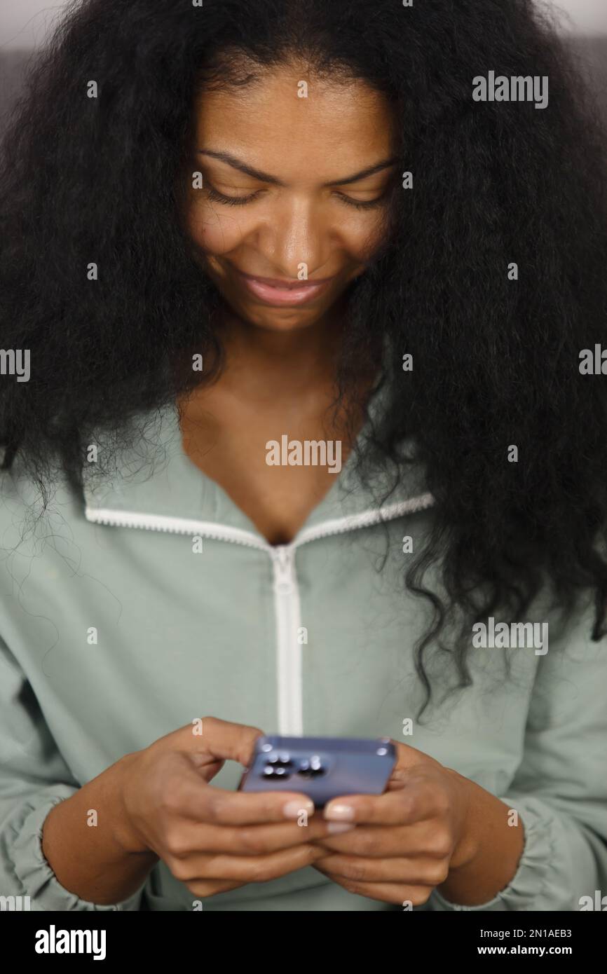 Closeup portrait of happy BIPOC woman typing text message on smart ...