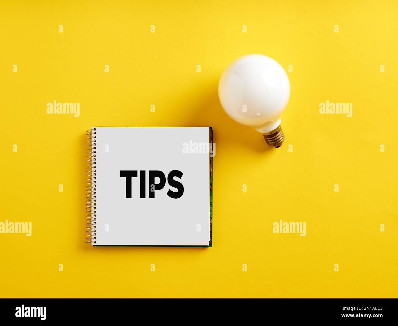 The word tips on notepad with a light bulb. Advice, support, assistance ...