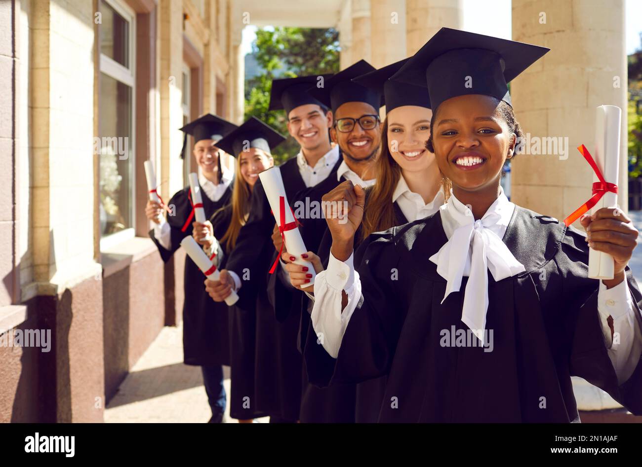 Happy successful diverse university graduates in caps and gowns ...