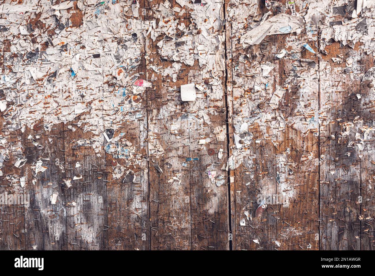 Old worn wooden notice board with scrap paper and rusty staples as ...