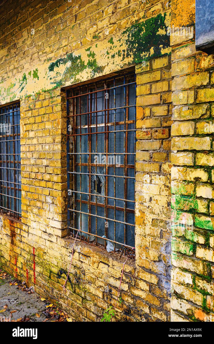 Old grid windows with broken glass on exterior wall of an old abandoned ...