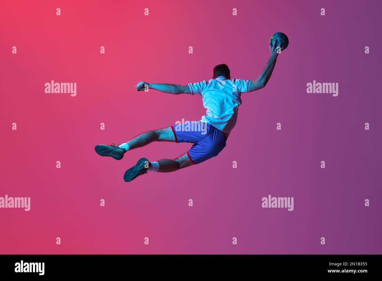 Back view. In a jump. Young man, professional handball player training ...