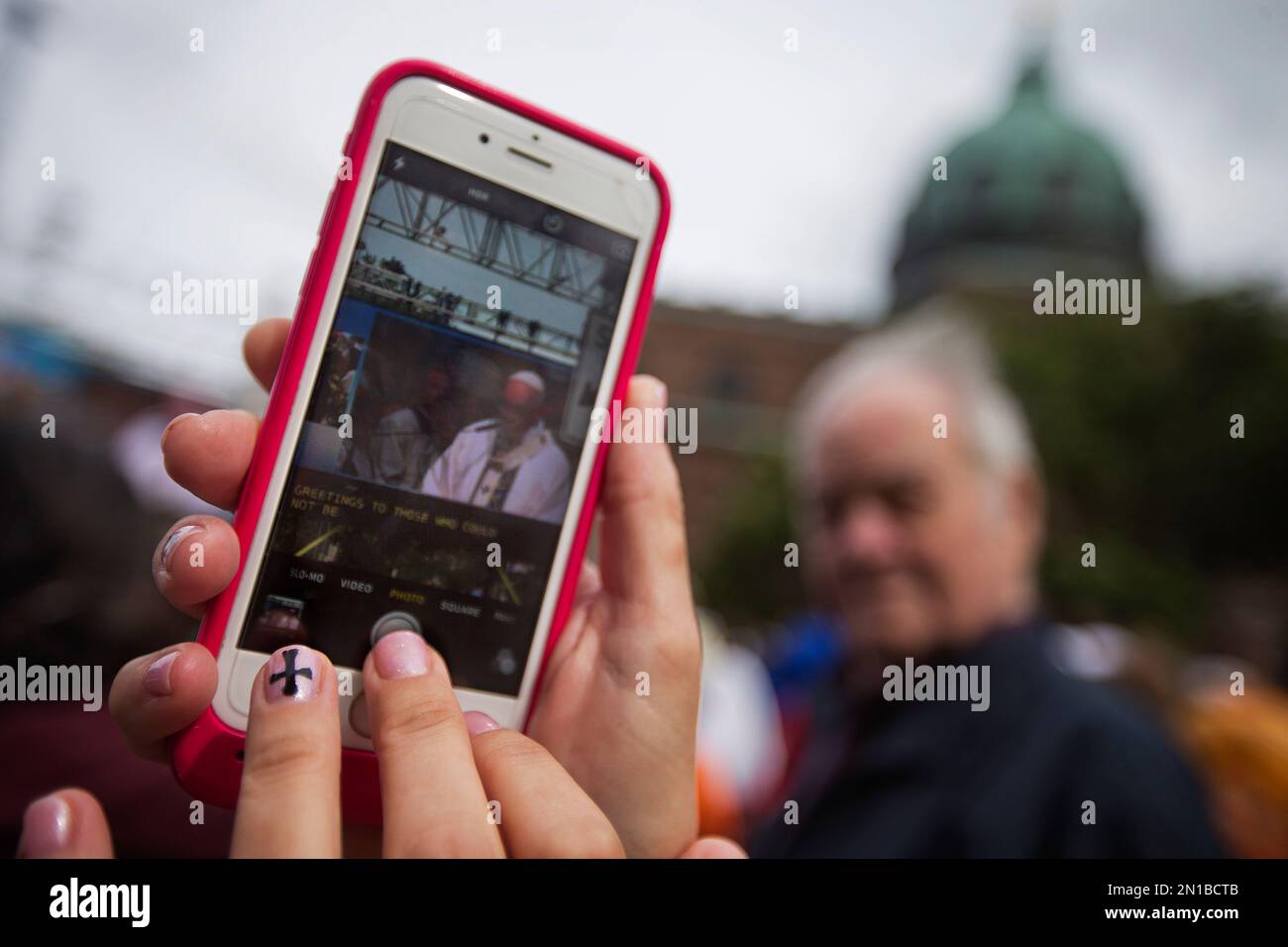 Mary Marko, of Troy, Mich., takes a photo of a big screen broadcasting ...
