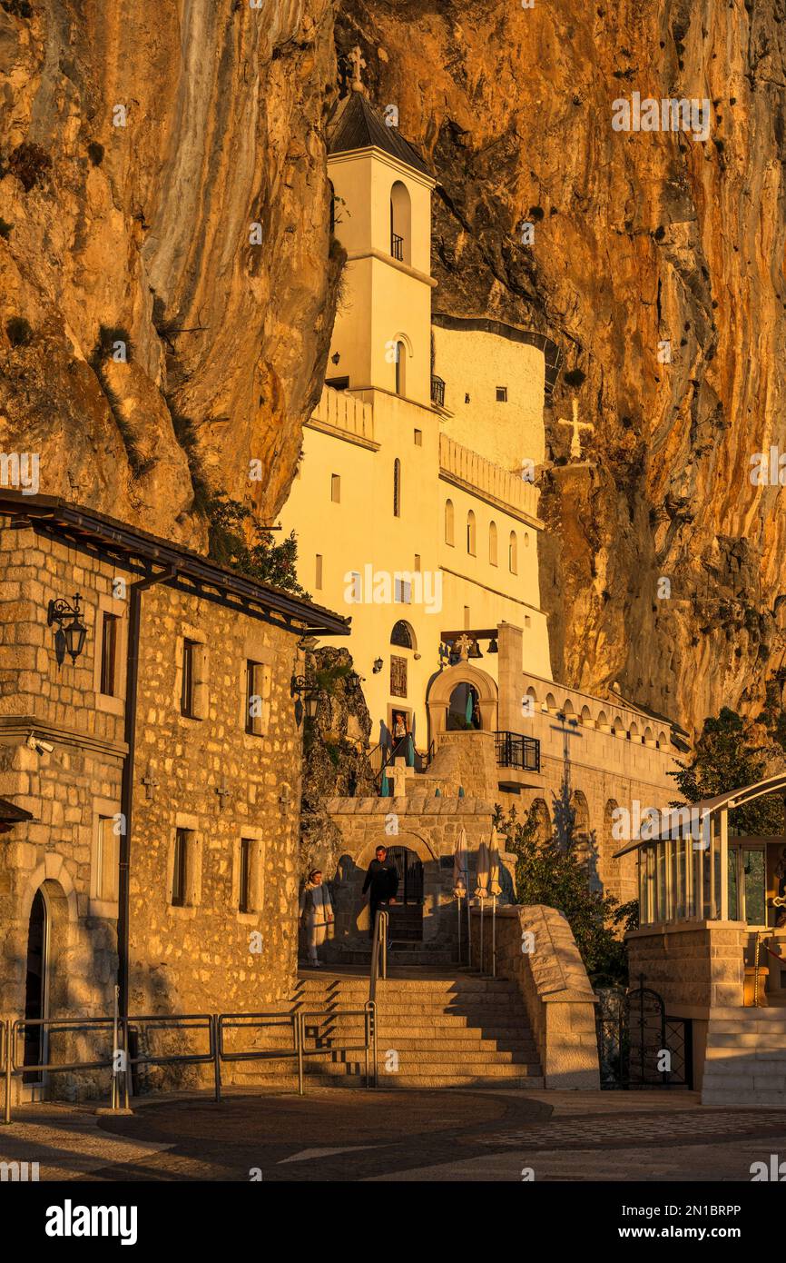 Façade of the upper church of Ostrog Monastery bathed in golden light ...