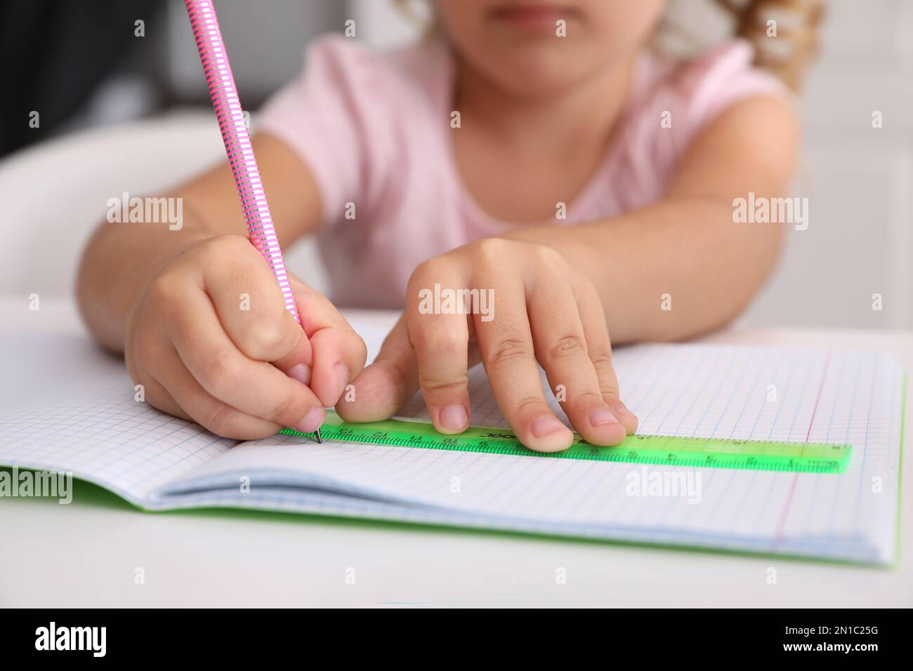 Little girl drawing with ruler and pencil at table, closeup. Doing ...