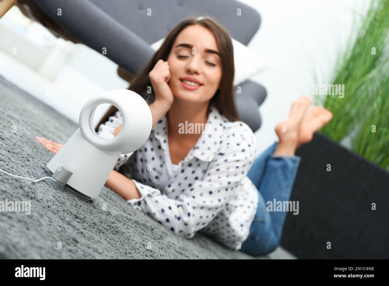 Woman enjoying air flow from portable fan at home. Summer heat Stock ...