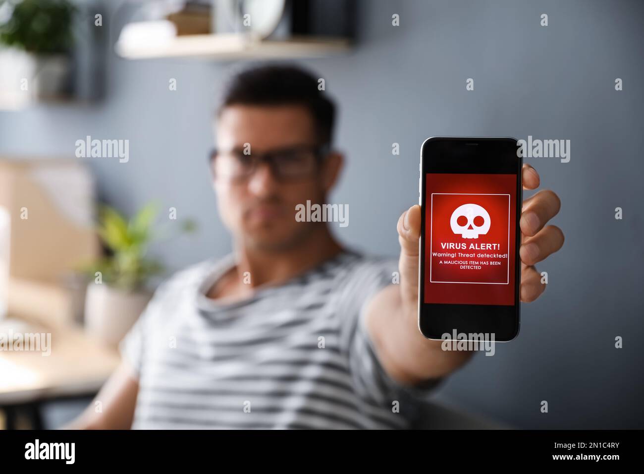 Man holding smartphone with warning about virus attack at home, focus ...