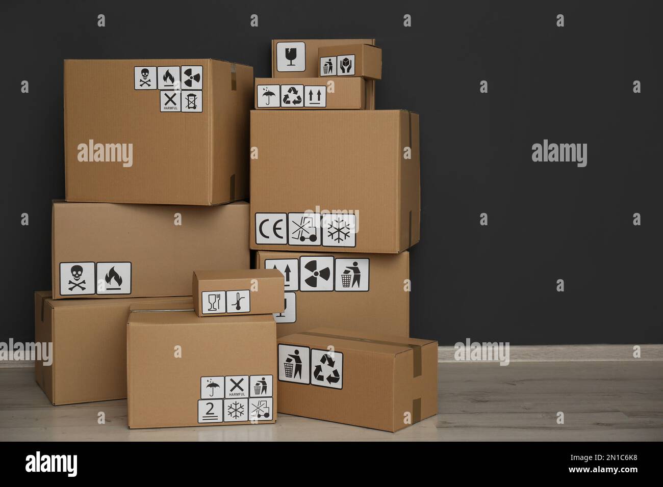 Cardboard boxes with different packaging symbols on floor near black ...