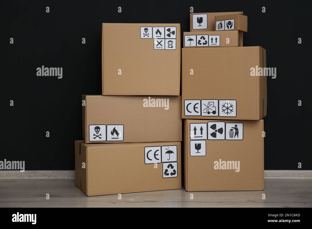 Cardboard boxes with different packaging symbols on floor near black ...