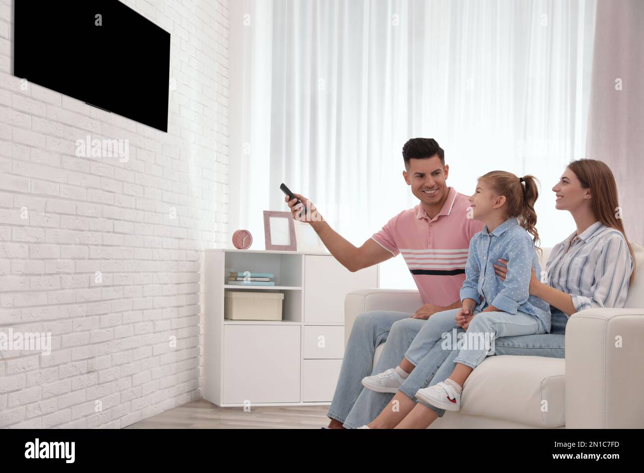 Happy family watching TV on sofa at home Stock Photo - Alamy