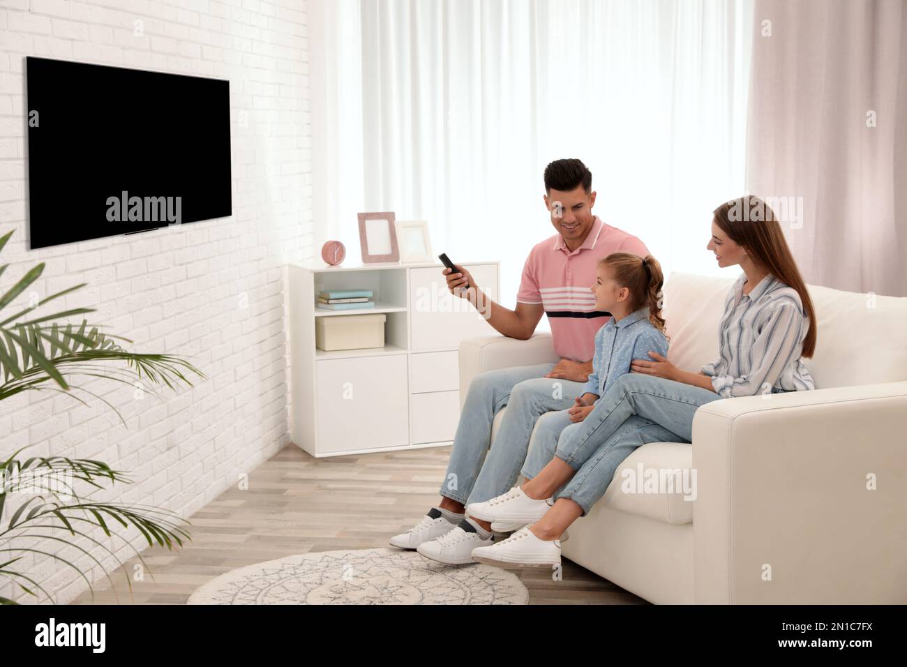 Happy family watching TV on sofa at home Stock Photo - Alamy