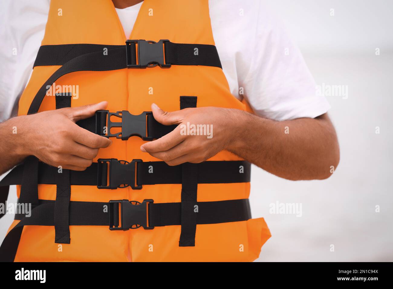Male lifeguard putting on life vest near sea, closeup Stock Photo - Alamy