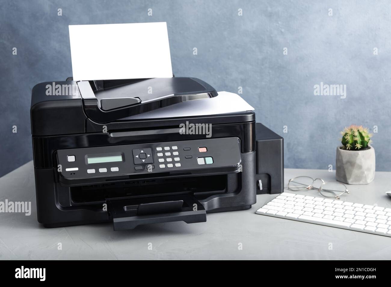 Modern printer with paper and computer keyboard on grey table Stock ...
