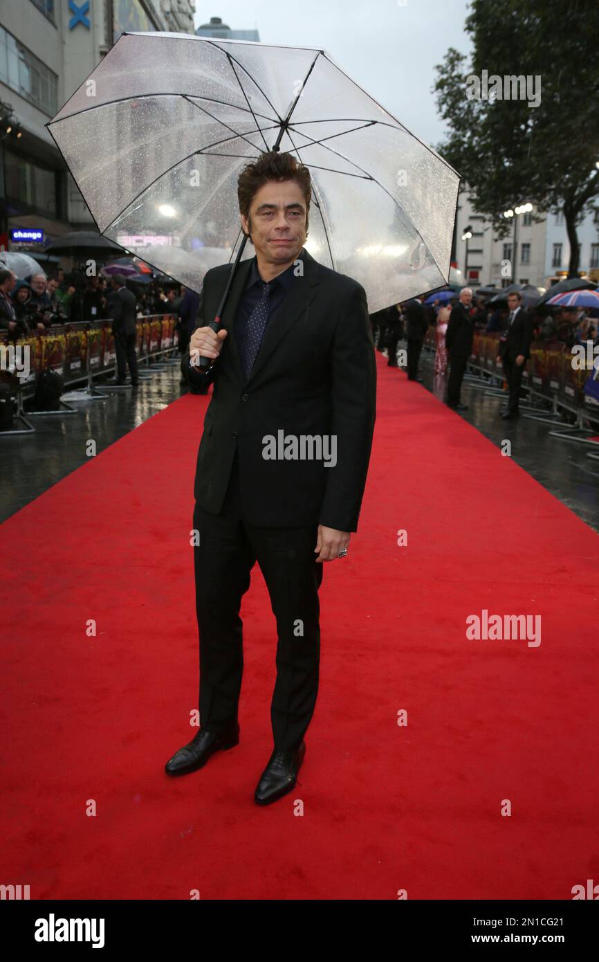 Actor Benicio Del Toro poses for photographs with an umbrella as he ...