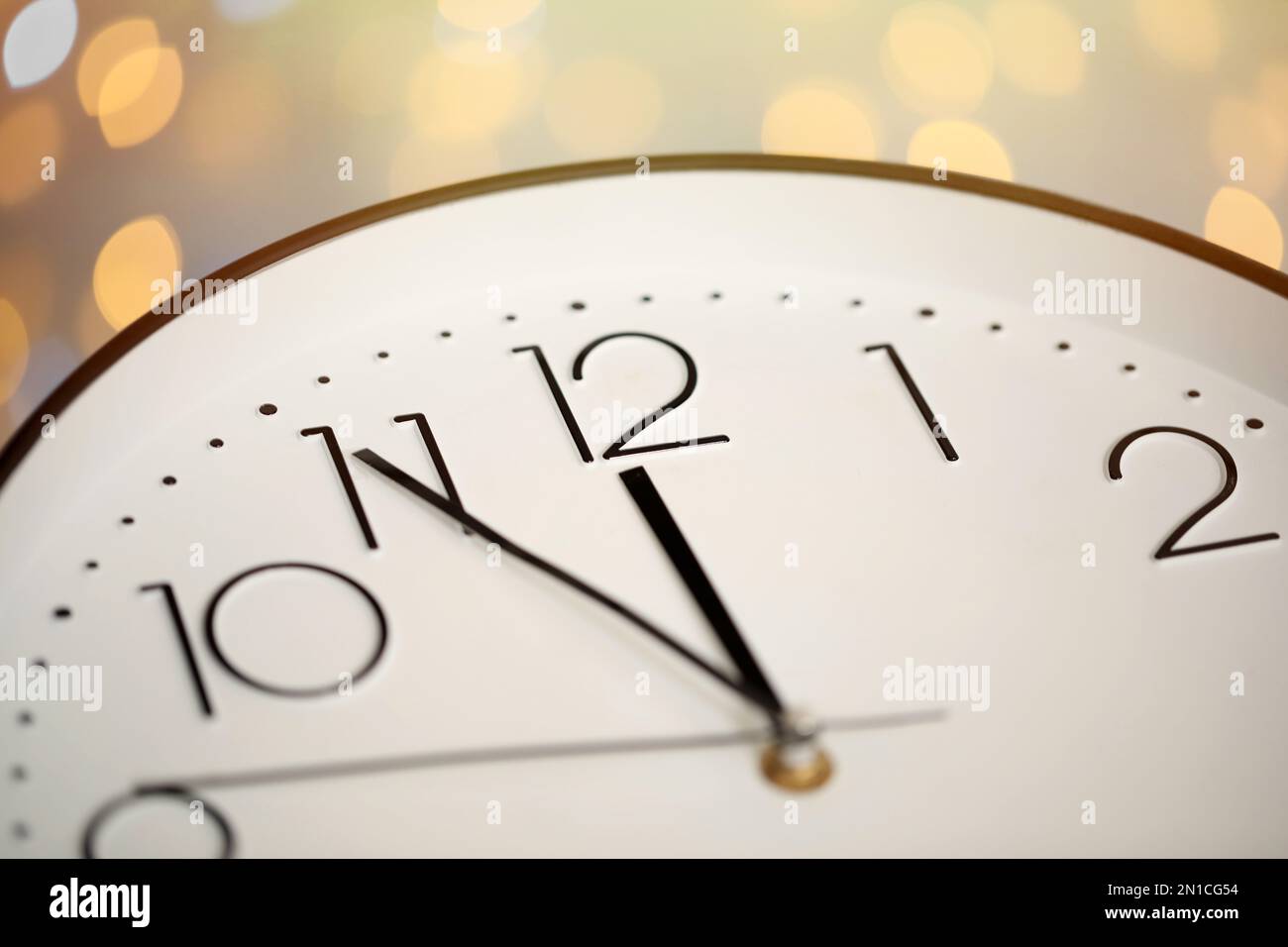 Clock showing five minutes until midnight on blurred background ...