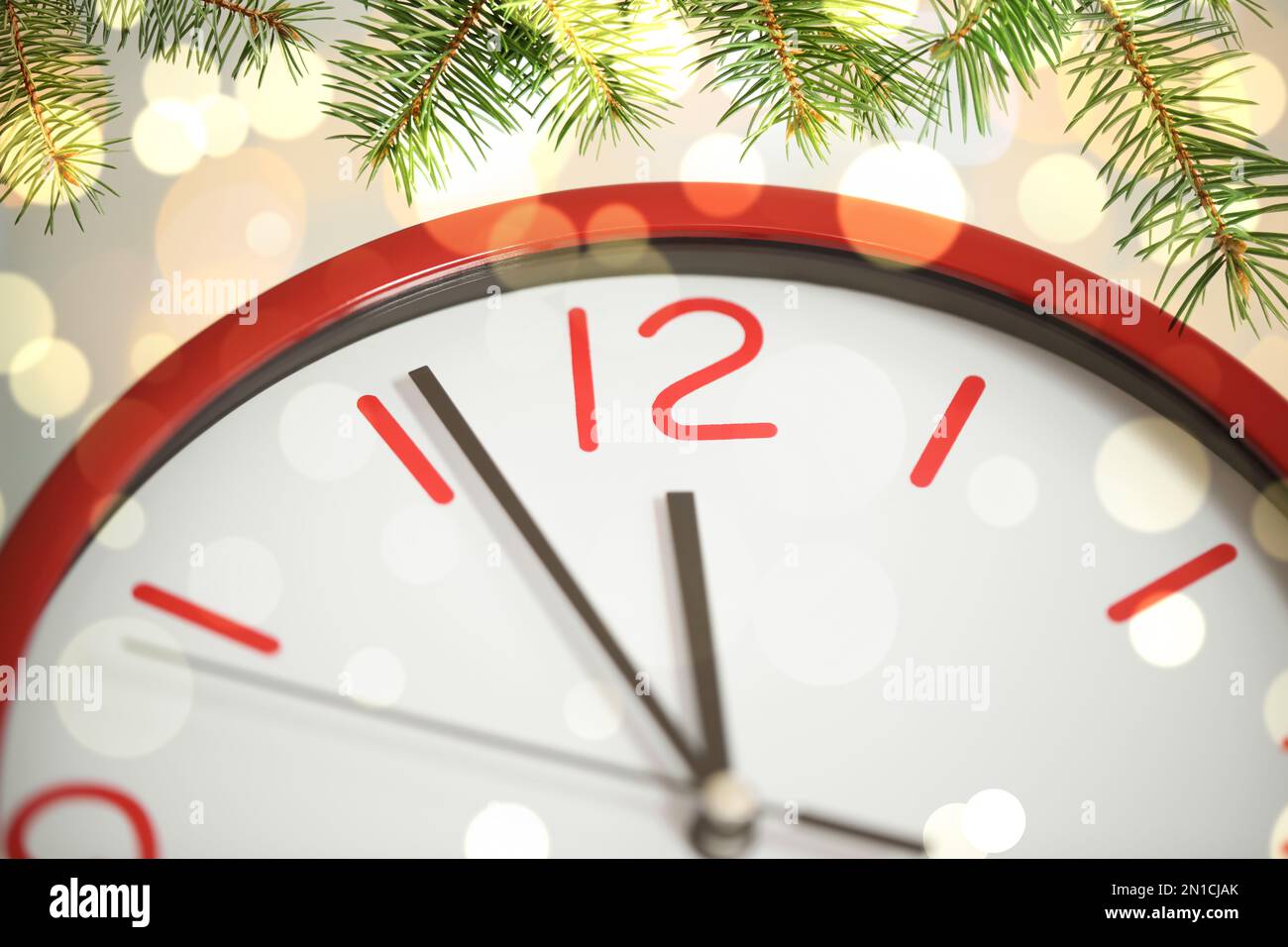 Clock showing five minutes till midnight with fir tree branches ...