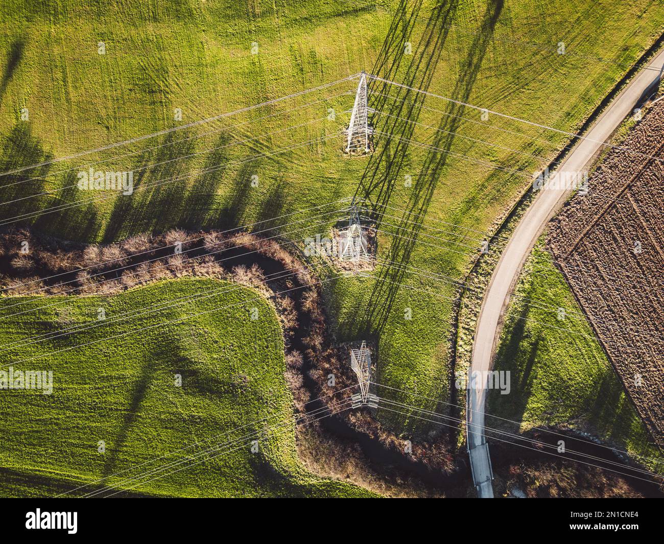 Top down view of three electrical towers standing on fields in the ...