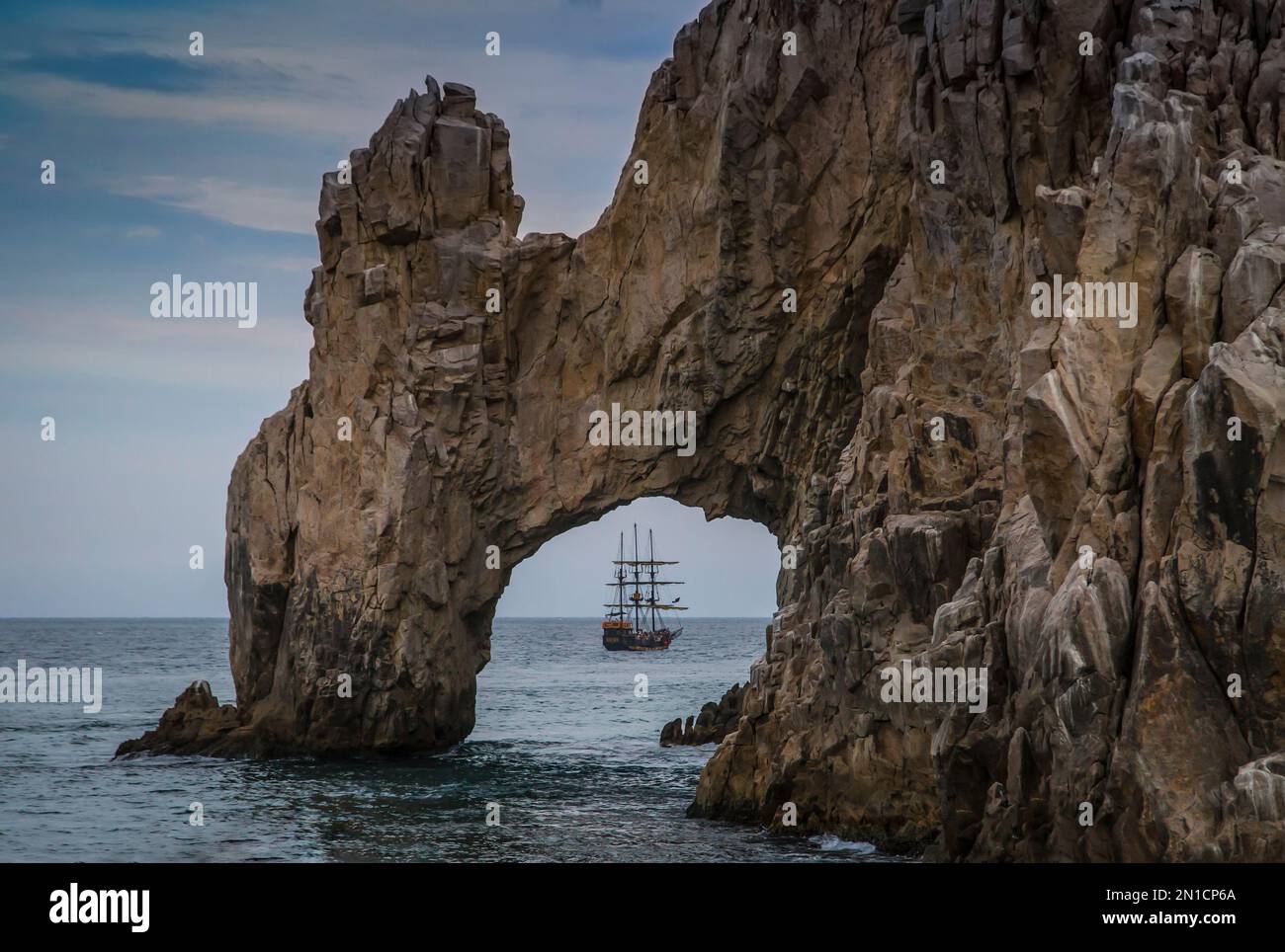 A huge rock formation on the sea with a view of ship in the background ...