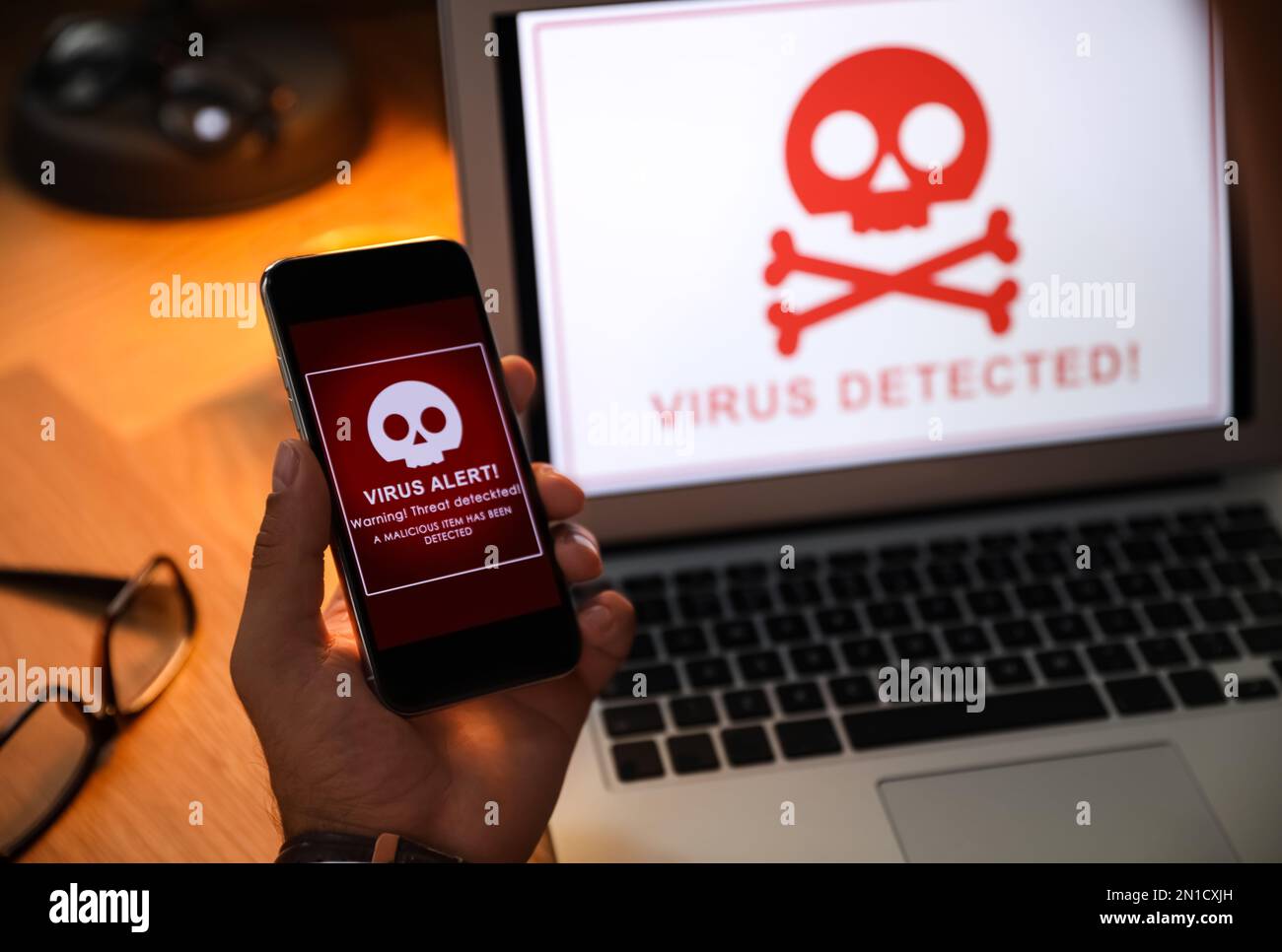 Man holding smartphone with warning about virus attack at table ...