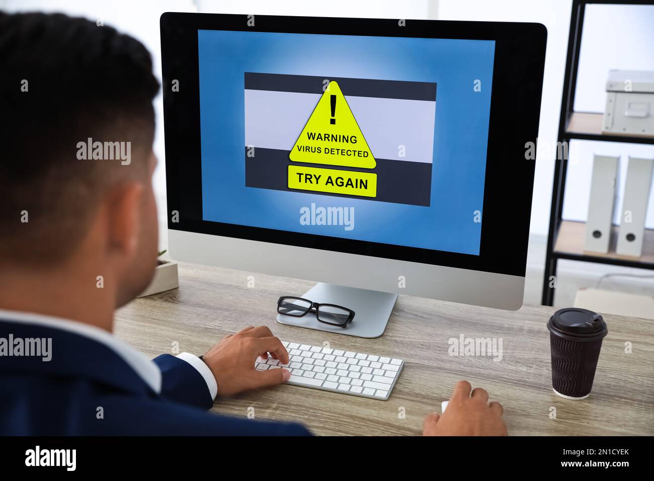 Office worker in front of computer with warning about virus attack on ...