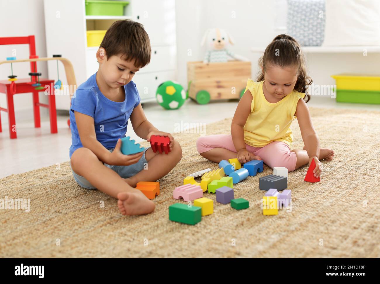 Cute little children playing with colorful blocks on floor indoors ...