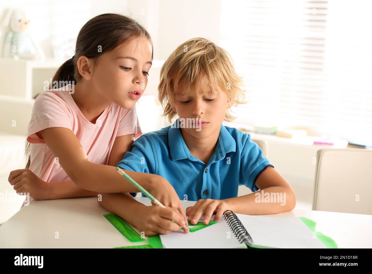 Little boy and girl doing homework at table indoors Stock Photo - Alamy