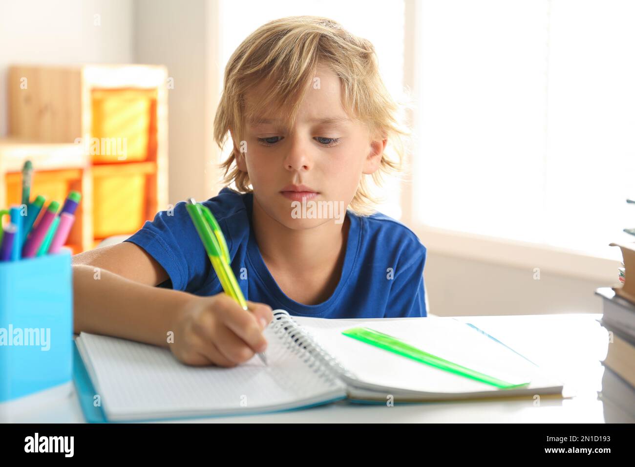 Little boy doing homework at table indoors Stock Photo - Alamy