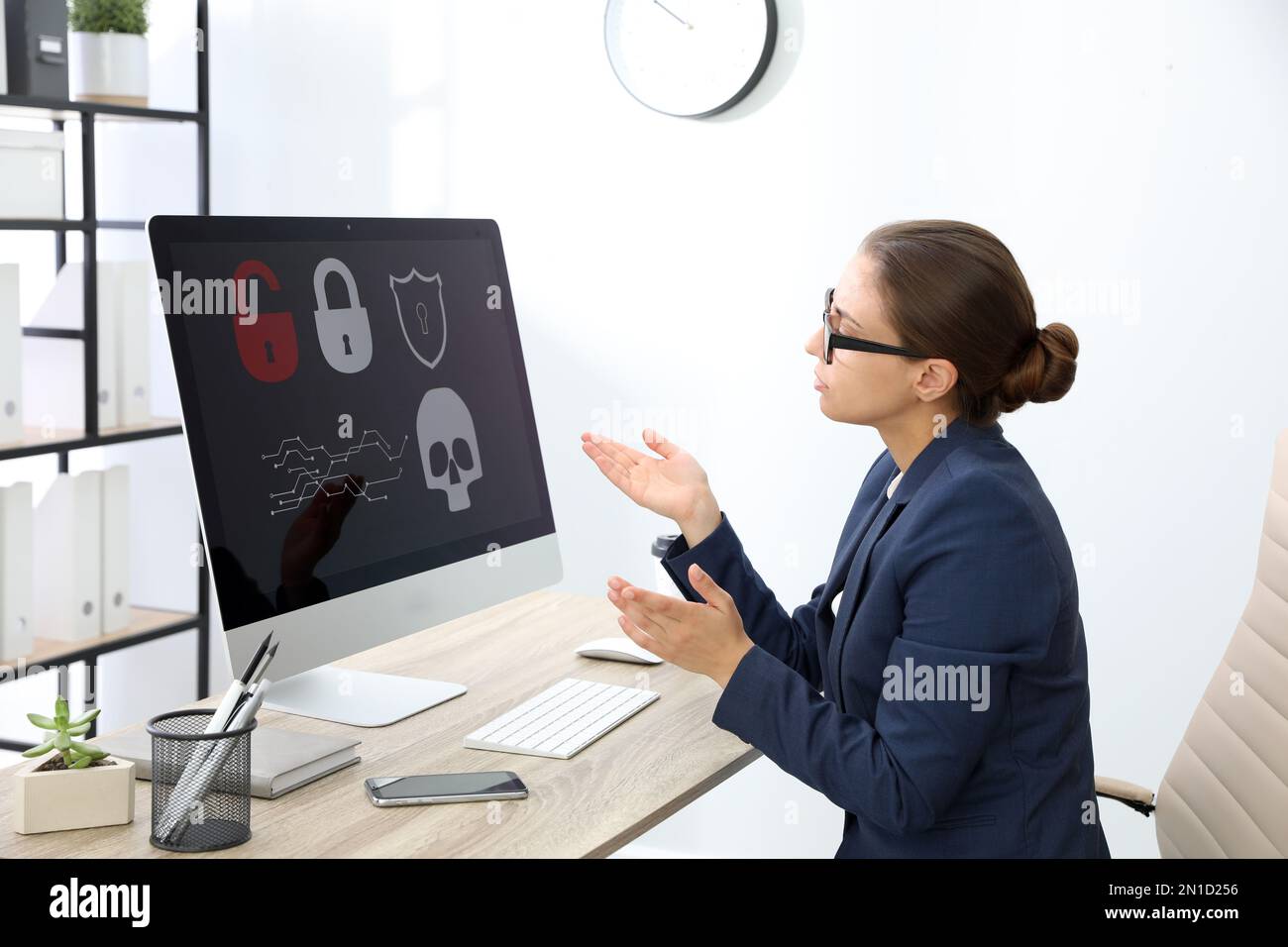 Office worker in front of computer with warning about virus attack on ...
