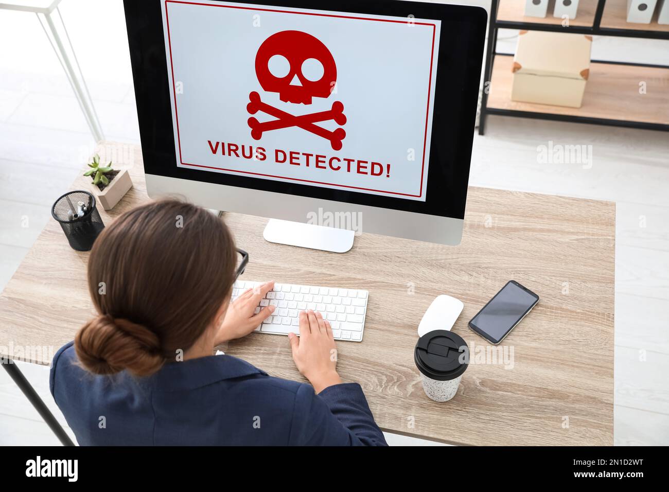 Office worker in front of computer with warning about virus attack on ...