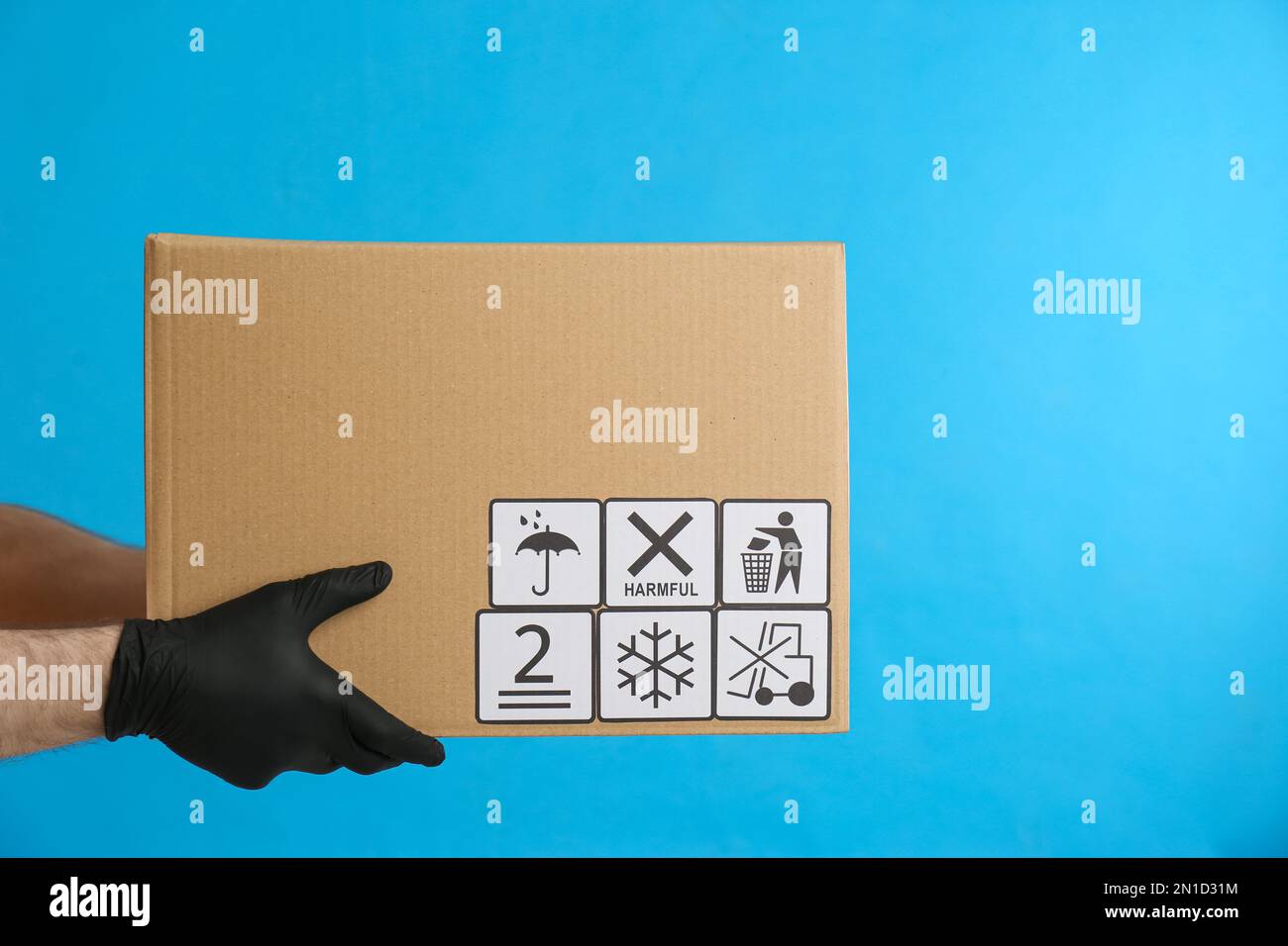 Courier holding cardboard box with different packaging symbols on blue ...