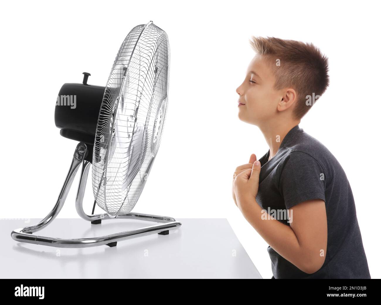 Little boy enjoying air flow from fan on white background. Summer heat ...