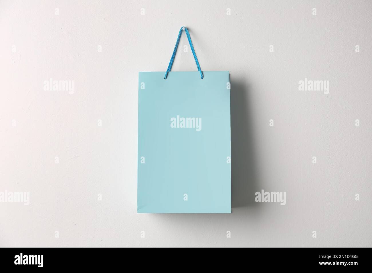 Paper shopping bag hanging on white wall Stock Photo - Alamy