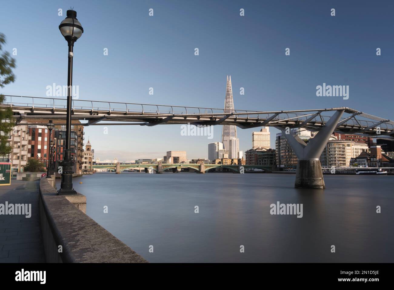 Wide shot of pedestrian bridge across Thames in London with Modern ...