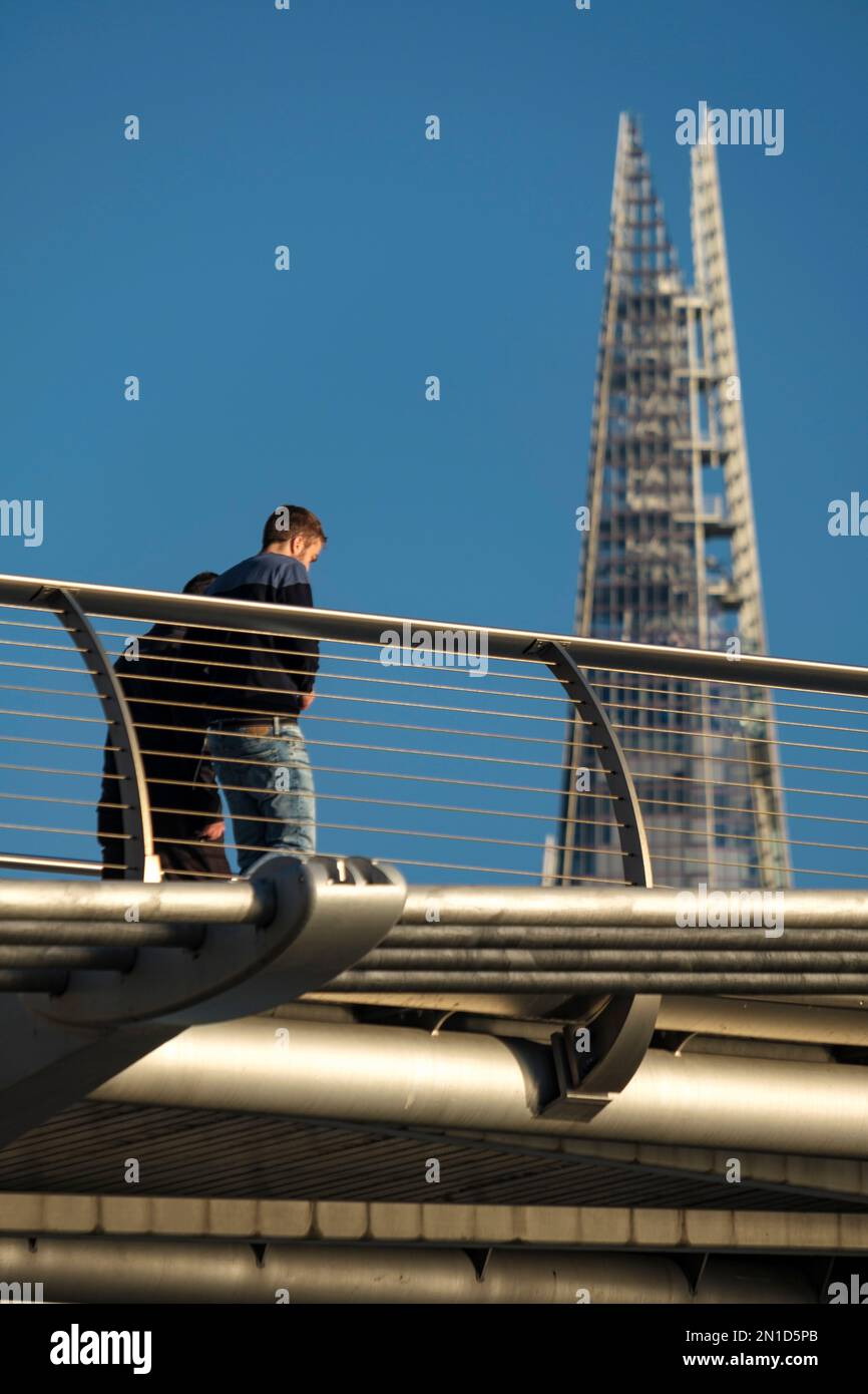 Mid shot of pedestrian bridge across Thames in London with Modern ...
