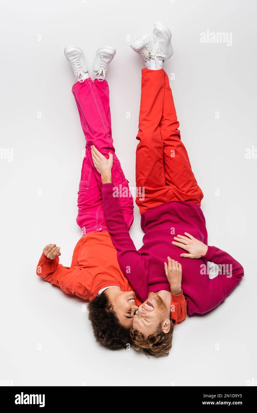 Top View Of Happy Interracial Couple In Magenta Color Clothes Lying