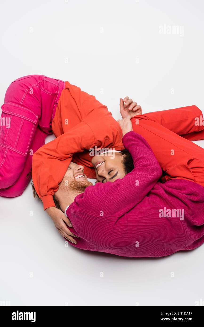 cheerful african american woman hugging with happy man in magenta color ...