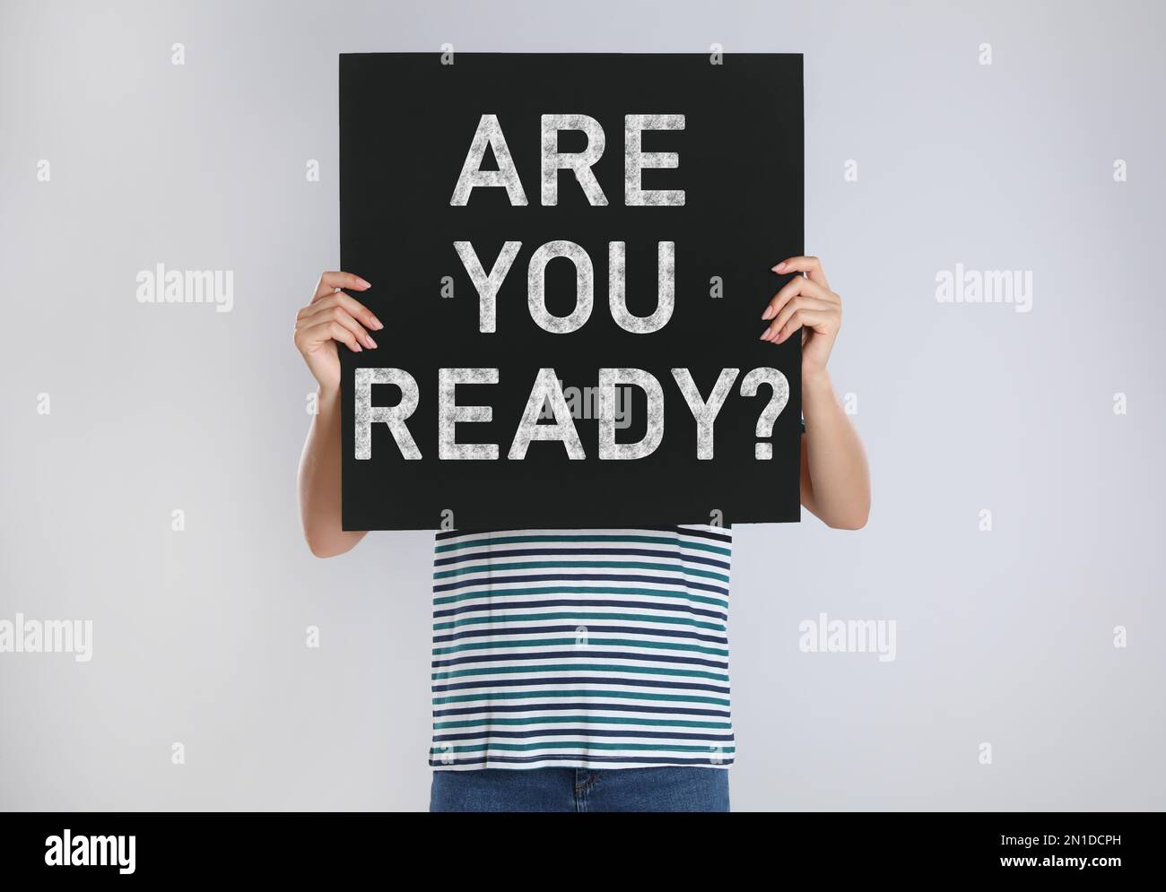 Woman holding poster with text Are You Ready? on light grey background ...