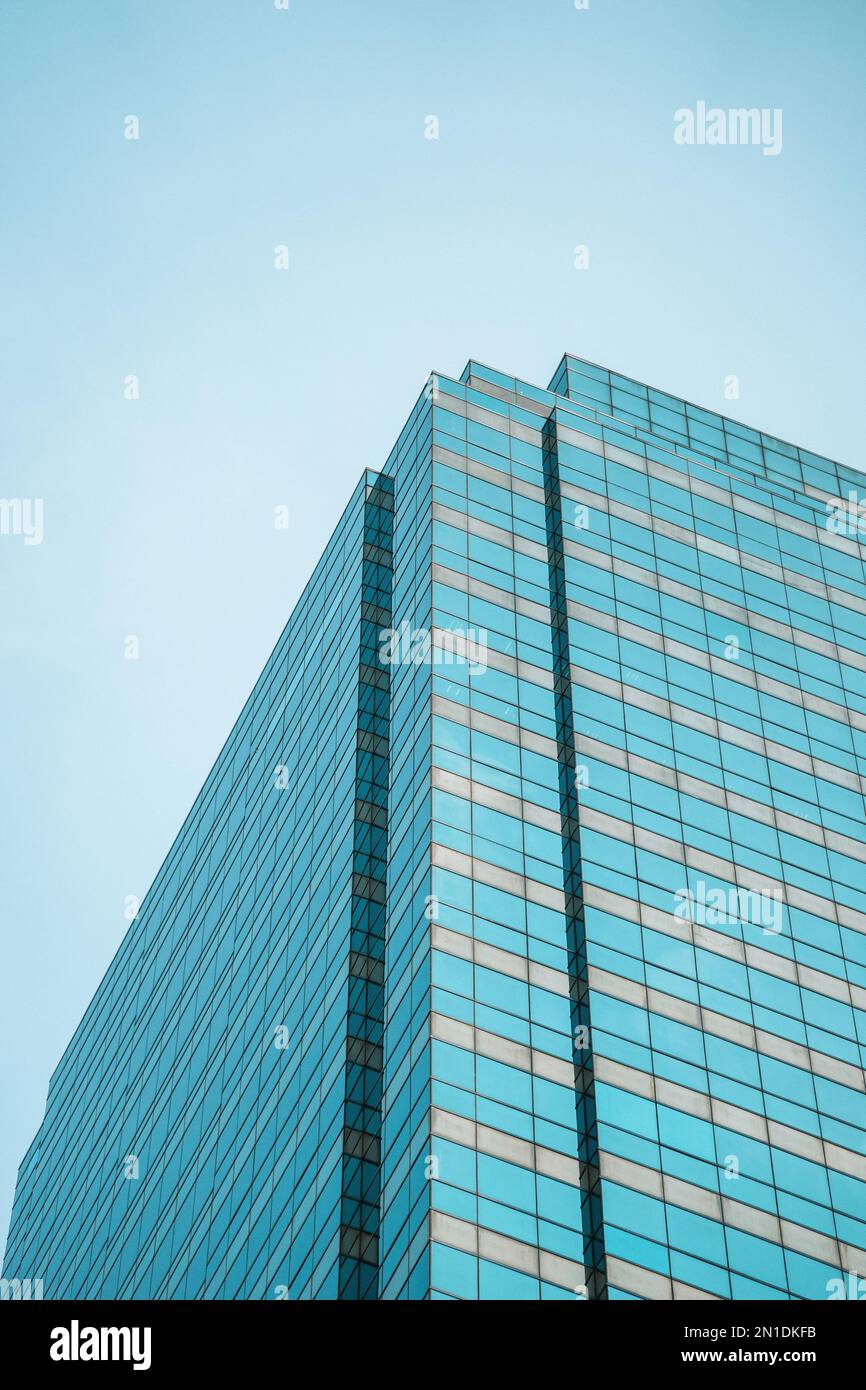 A low-angle shot of a tall glass office building with lots of windows ...