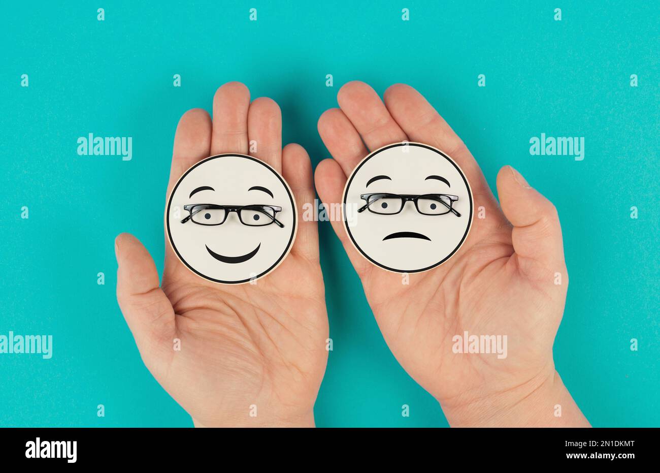 Holding a head with a sad and a happy face in the hands, mental health ...